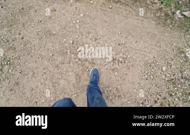 Man's legs in jeans and trainers walking along the dirty place with a ...