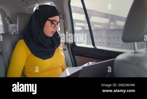 Business woman in Hijab uses laptop sitting in back seat of car. Modern ...