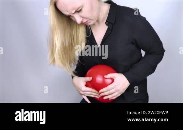 Bloating and flatulence concept. The woman holds a red balloon near the ...