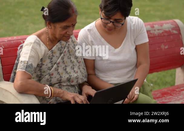 Young Indian woman helping her old retired mother on a laptop sitting ...