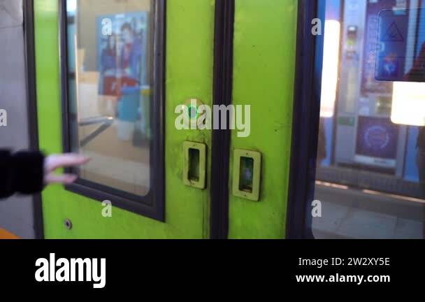 Close-up of girls hand pressing green button of the train door to open ...