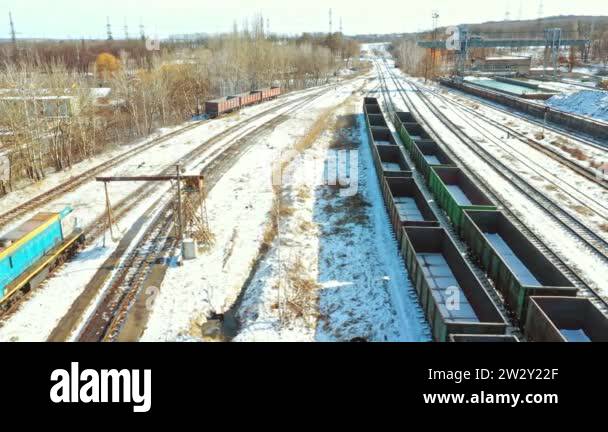 A freight train pulls a trailer with containers behind on the railroad ...
