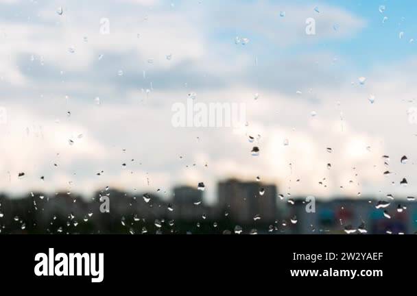 Drops falling on glass during rain. Raindrops on the glass. Cloudy and gloomy rainy weather. The ...