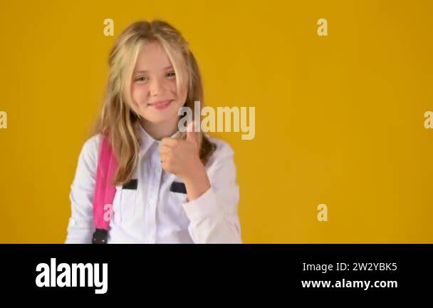 Happy smiling blonde teenager girl jumping into the frame shows thumbs ...