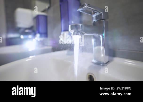 Hot tap water. Warm water flows from the tap in the bathroom ...