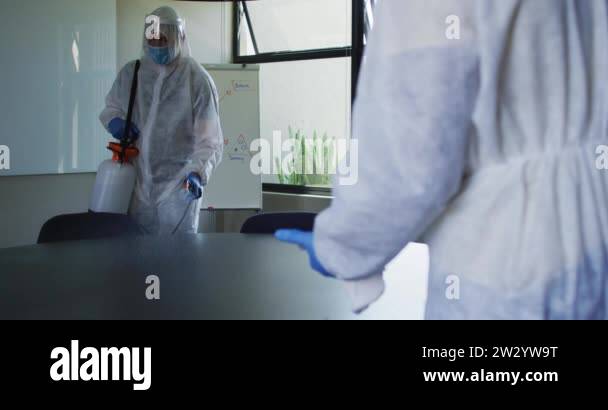 Team of health workers wearing protective clothes cleaning the office ...