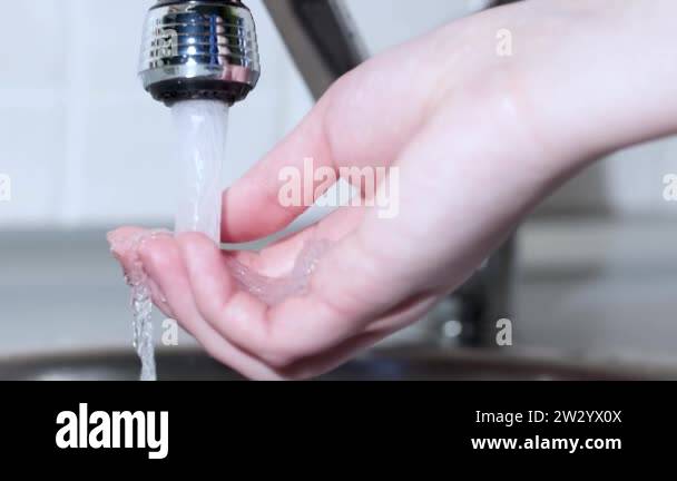 A man opens a water tap in the kitchen and washes his hand. Closing the ...