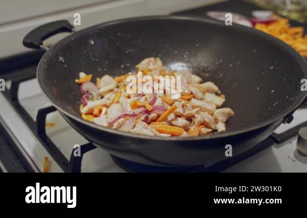 Roasting vegetables and chicken in a wok over a fire. Cooking Asian ...