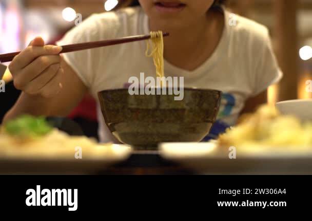 4K Asian woman eating beef noodles for dinner in a restaurant. Using ...