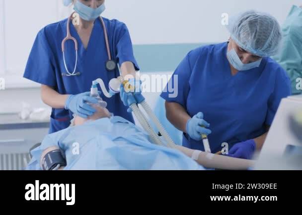 The anesthesiologist in medical gloves prepares female patient for ...