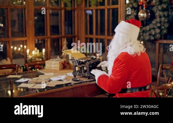 Back view of Santa Claus sitting on the chair at and printing a letter ...