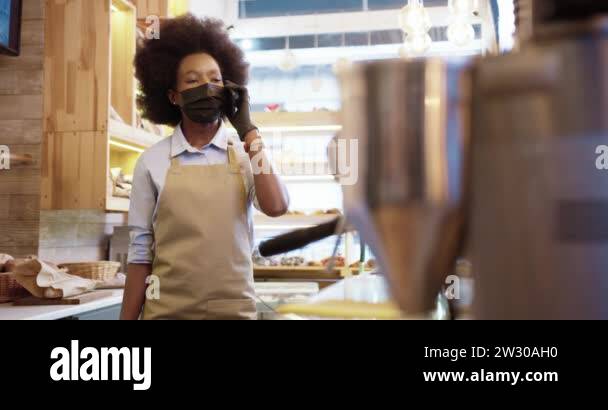 Beautiful African American young woman seller in bakery shop standing ...