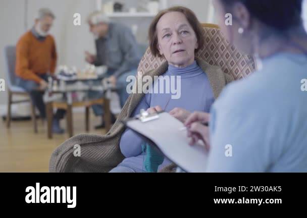Smiling mature Caucasian woman knitting and gesturing yes by shaking ...
