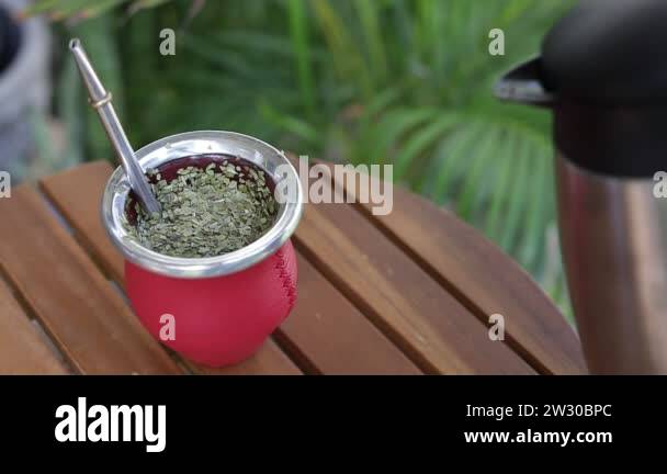 Man making yerba mate tea. Close up pouring hot water into traditional ...