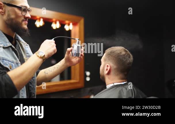 Barber sprays parfume on client in barbershop after haircut and styling ...