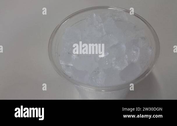 Crystal clear ice cubes in the cold cup of water. Closeup view of water ...