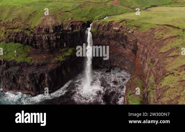 Stunning waterfall splashing from cliff aerial view. Mulafossur ...