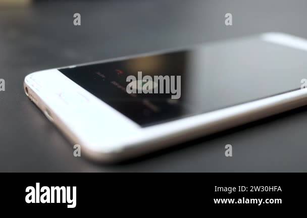 The smartphone is placed on the table with an incoming call and finger ...