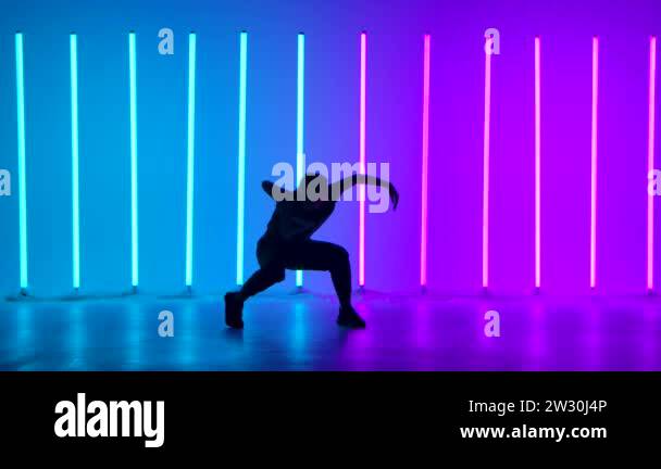 Young woman dancing street dance hip hop in a studio with neon lighting ...