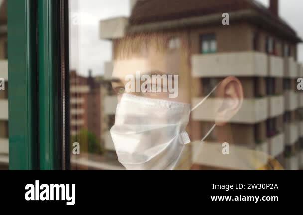 sad young man in quarantine. A teenager in a facial medical mask looks ...