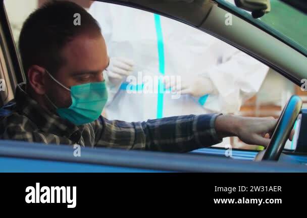 Medical worker performing drive-thru COVID-19 test, taking nasal swab ...