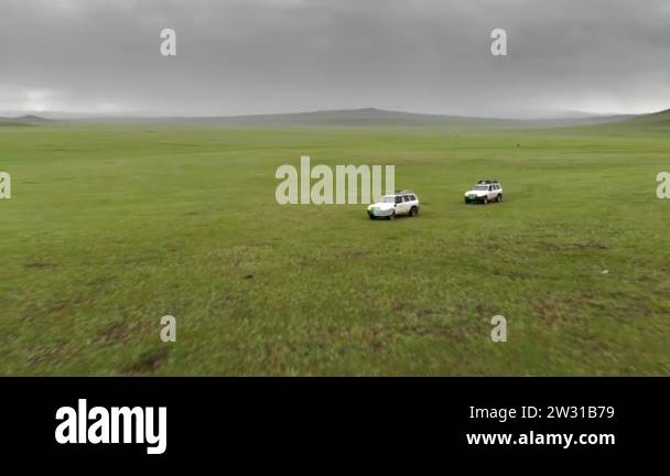 Two 4X4 suv cars driving in the treeless vast meadow. Crossing ...