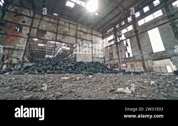 Big old empty factory with garbage and a pile of used rubber tyres ...