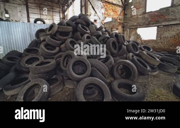 Landfill of used automobile tires on the old abandoned plant inside. Huge piles of black waste ...