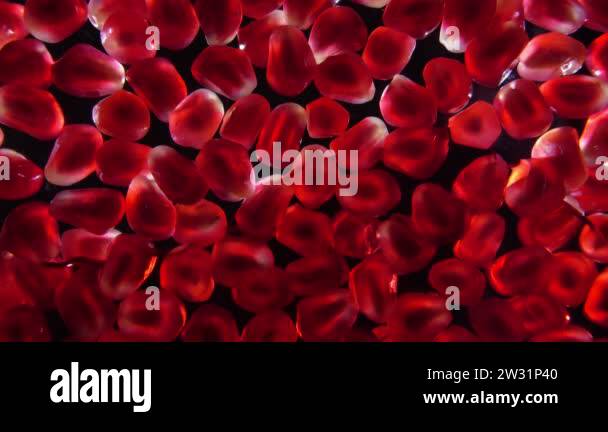 Juice is flowing on shining pomegranate grains laying on the black ...