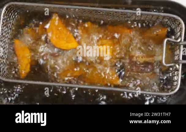 Male cook shaking a lattice with slices of potatoes rustic and meat in ...
