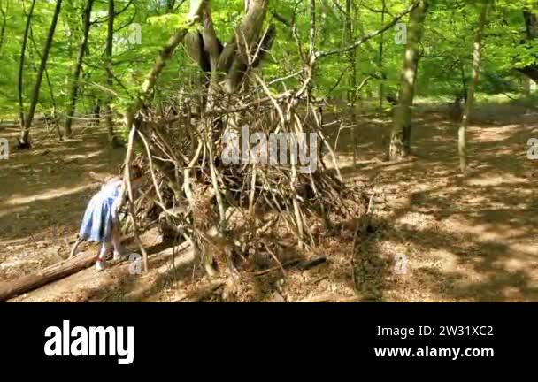 Little girl playing in the wickup, the hut made of btree brunches in ...