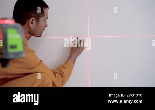 a man builder dressed in work clothes measures the level with a ...