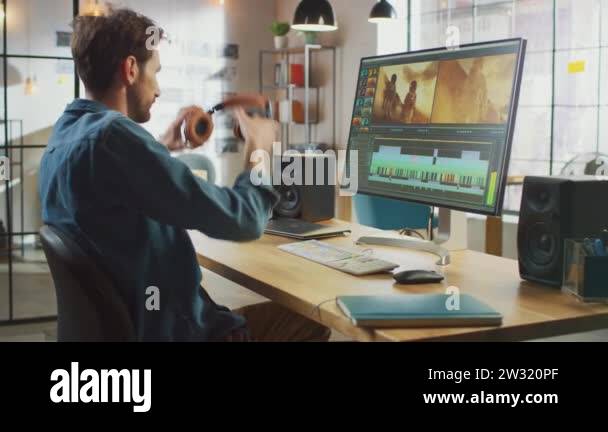 Male Video Editor Puts Headphones and Starts Working with Footage on ...