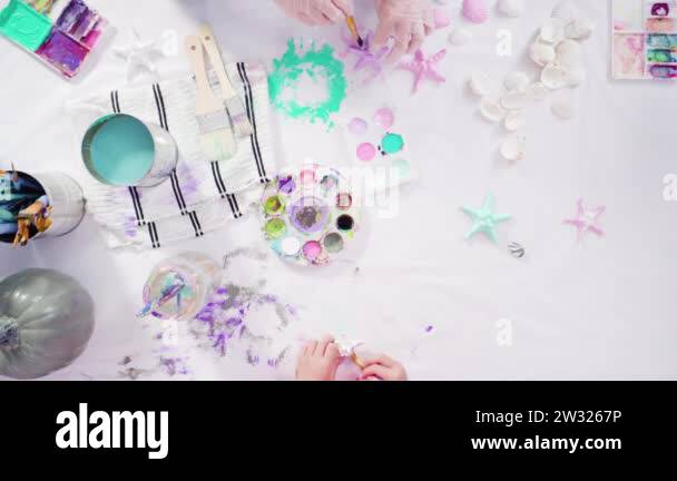 Little girl painting paper mache figurines with acrylic paint for her ...