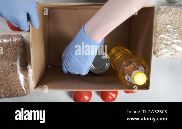 putting grocery food in carton donation box: vegetables, oil, cereals ...