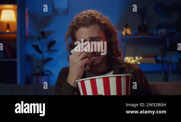 Young cute guy crying and wiping tears with paper napkin while sitting ...