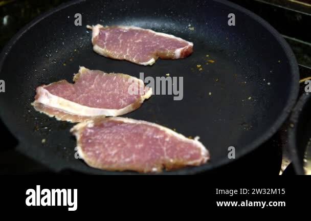 4K, A cheff is cooking a pork tenderloin fried in pan at kitchen. Pork ...
