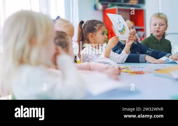 Children with their teacher together at round table in class. Little ...