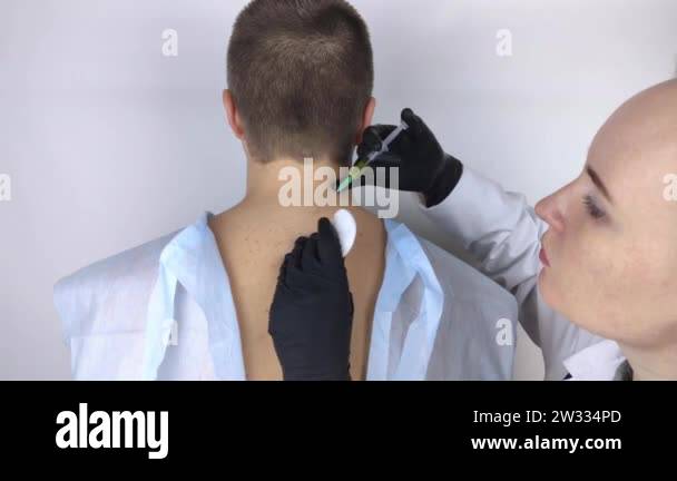 An orthopedic surgeon gives an injection in the cervical vertebrae ...