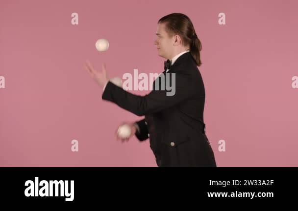 Man juggler shows tricks with white balls, tossing and catching them. A ...