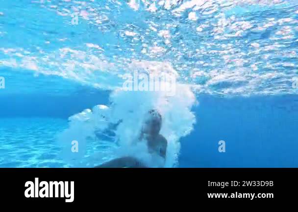 Boy jump into the blue clear water making many bubbles. Young boy ...