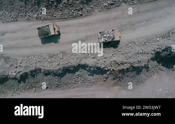 Mining dump trucks in large granite open pit mine. Loaded truck rides ...