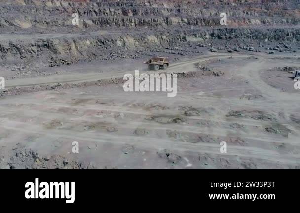 Mining dump trucks in large granite open pit mine. Loaded truck rides ...