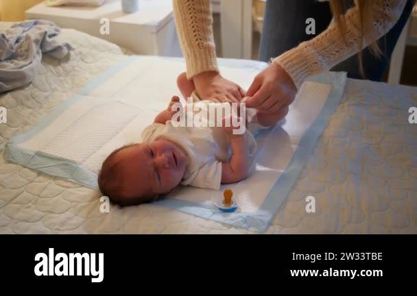 Young mother changing messy diapers to her newborn baby boy crying on ...