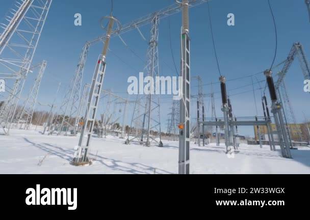 Poles and cables of power plant in winter. Action. Power plant in field ...