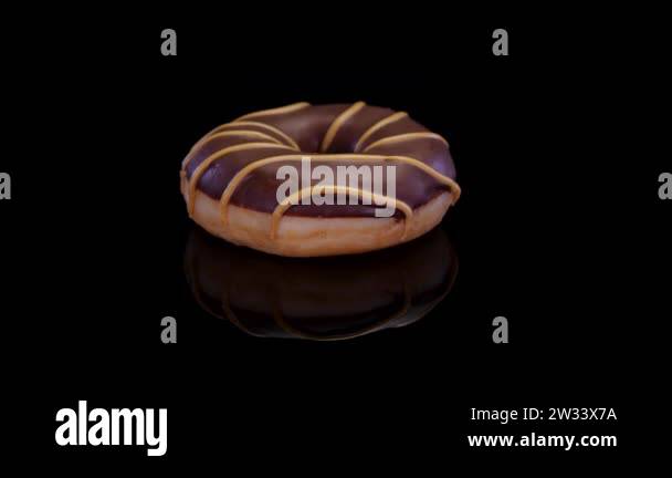 Donut with chocolate caramel icing rotating on a black background ...
