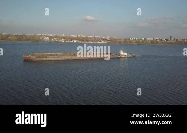 A tugboat ship pushes a barge upstream of the river to transport bulk ...