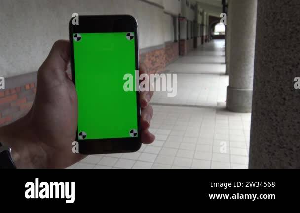 4K caucasian man show the Green Screen phone in aisle with columns ...