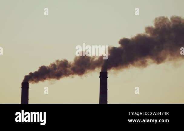 Two pipes with thick dirty smoke filling the air. Dark fumes going from ...