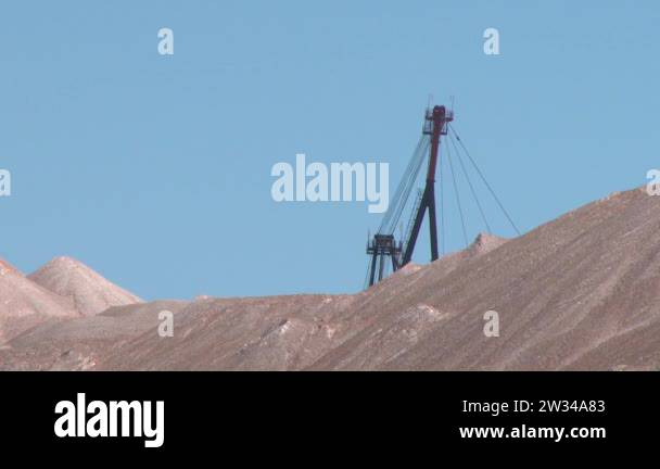 Quarrying mineral resource with machinery. Crushed stones pouring from ...